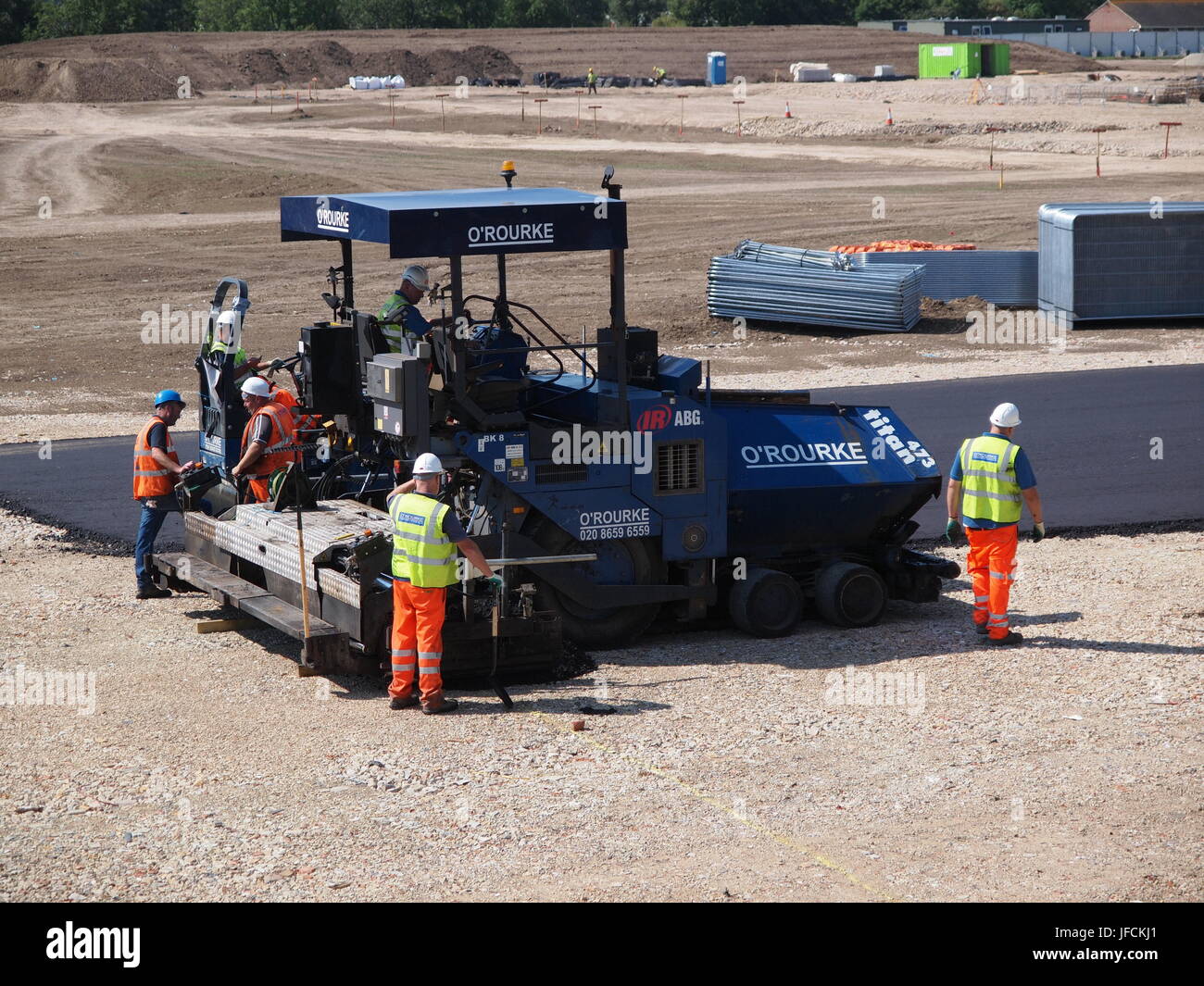 A large blue paving machine laying asphalt Stock Photo - Alamy