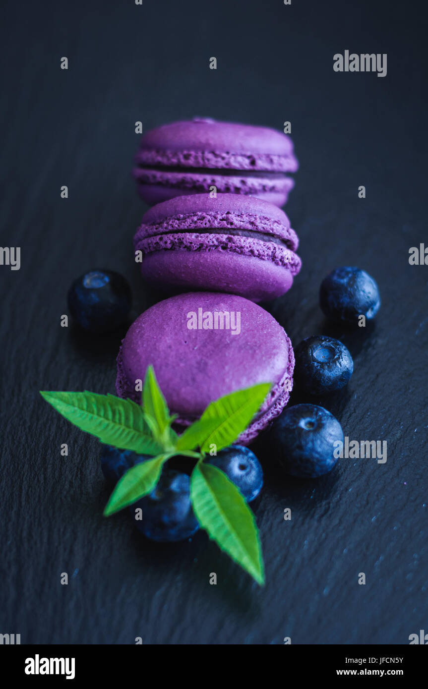 pink macaroons with blueberries on black background Stock Photo - Alamy