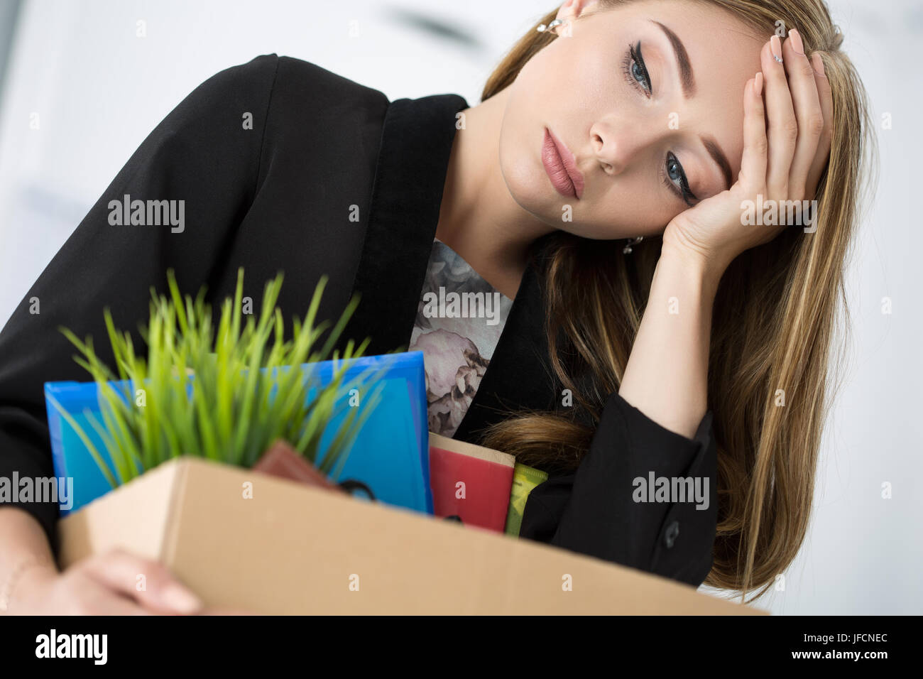 Young dismissed female worker in office holding carton box with her ...