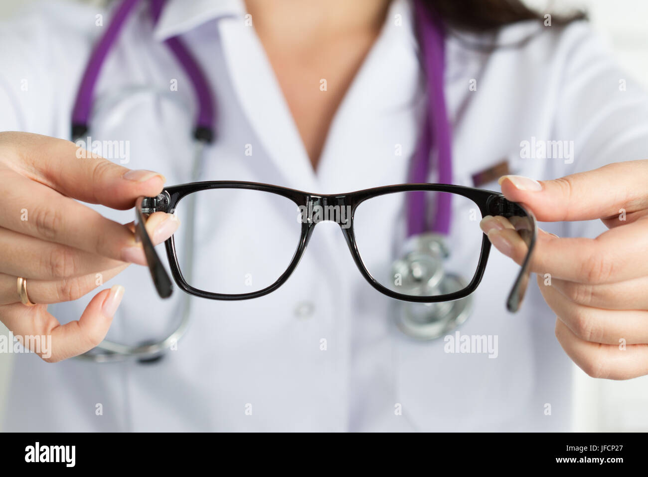 Female oculist doctor hands giving pair of black glasses to patient ...
