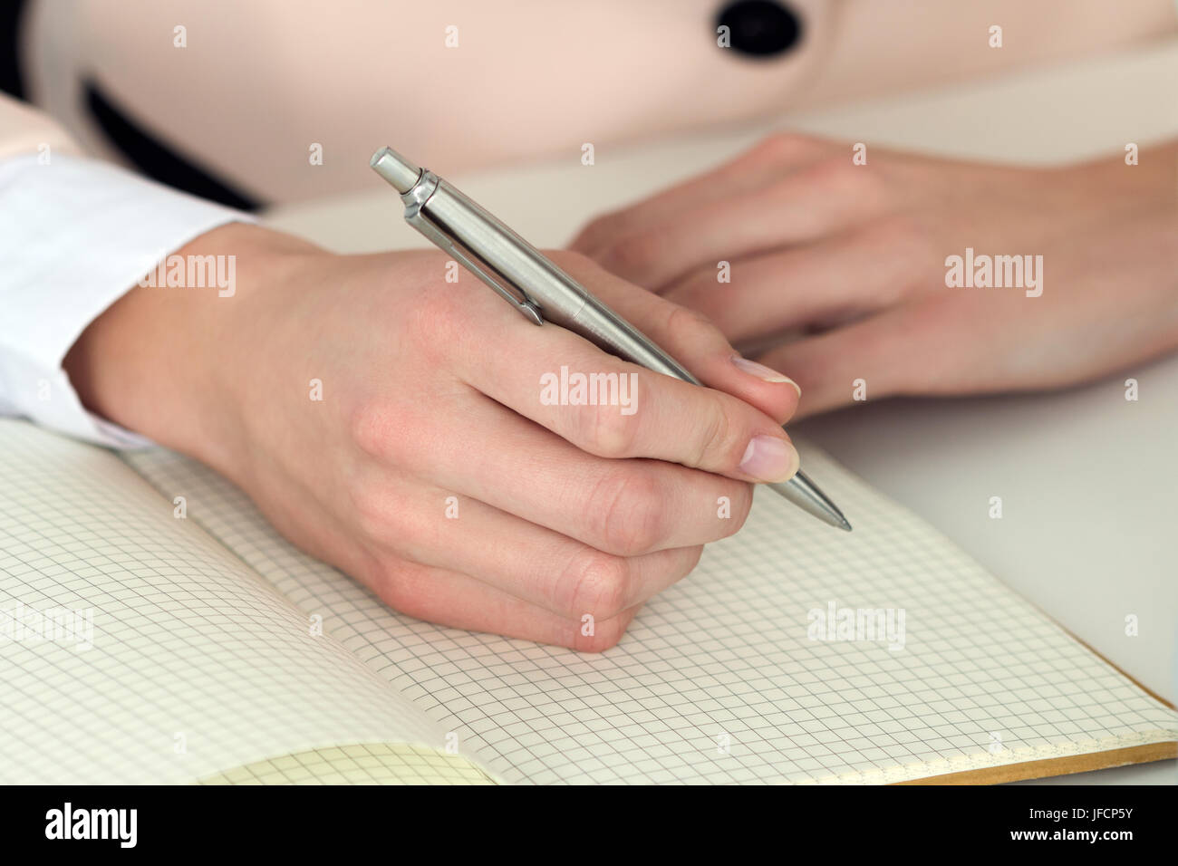 Woman hand holding silver pen ready to make note in opened notebook ...