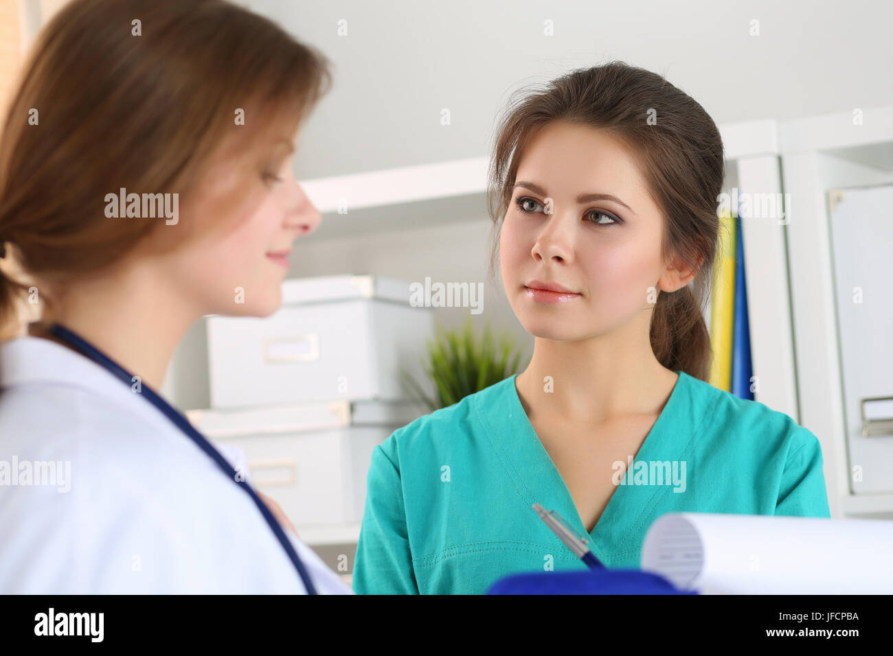 Two beautiful female medicine doctors working at their office ...