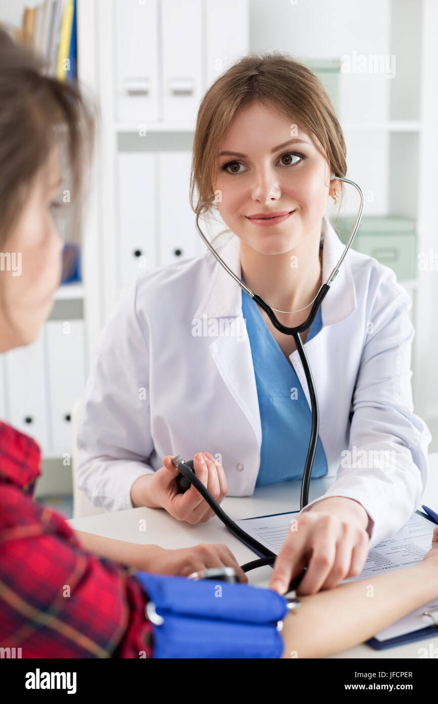 Smiling female medicine doctor measuring blood pressure to patient ...