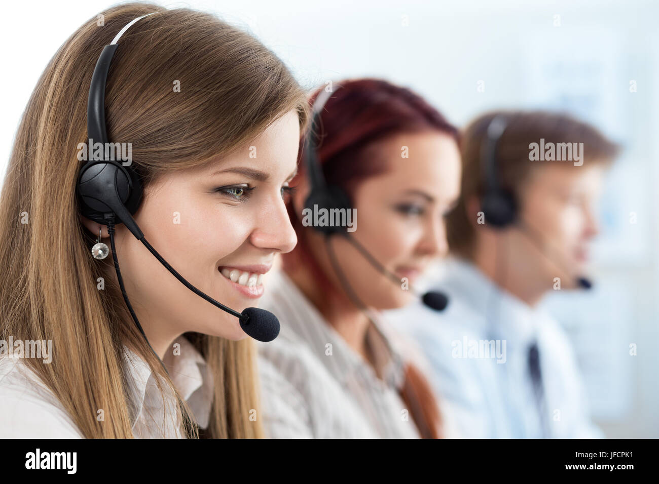 Portrait of call center worker accompanied by her team. Smiling ...