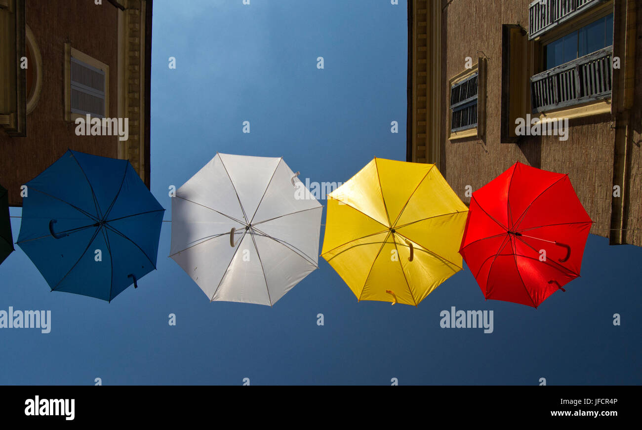 umbrellas of different colors over the street with blue sky as ...