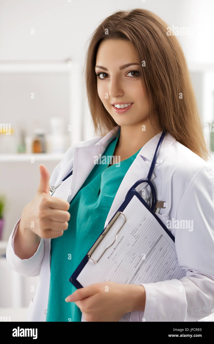 Smiling female doctor showing OK sign with thumb up standing at her ...