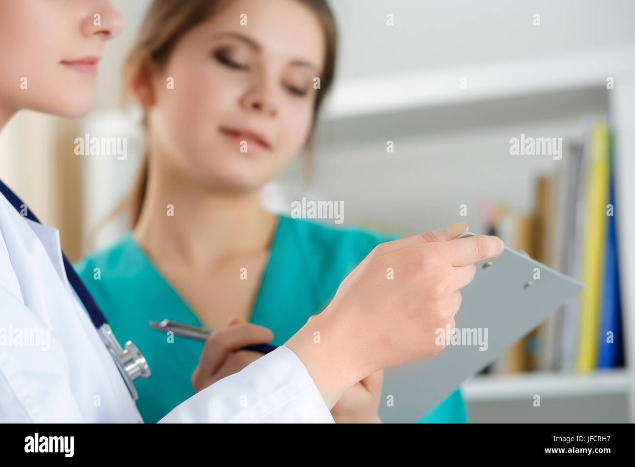 Two female medicine doctors working at their office discussing diagnose ...
