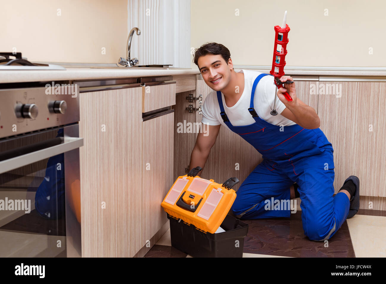 Young repairman working at the kitchen Stock Photo - Alamy