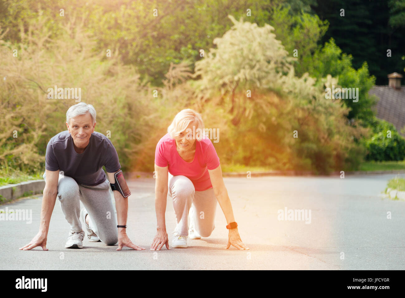 Crouch start. Positive active senior couple sitting in the special ...