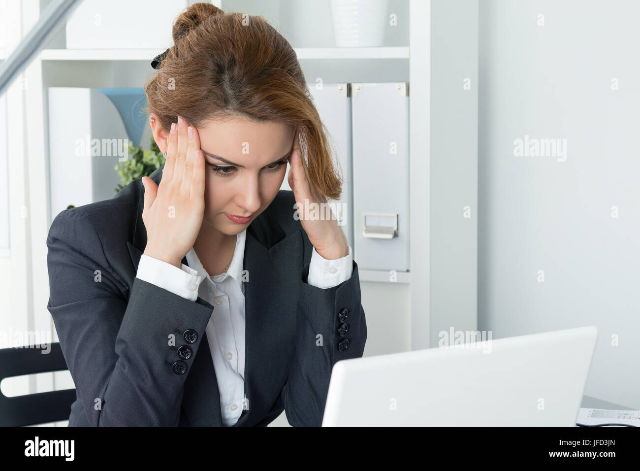 Young beautiful business woman trying to concentrate looking at laptop ...