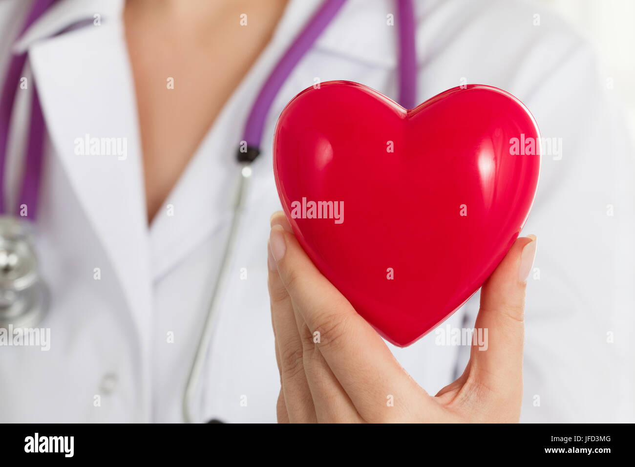 Female doctors's hands holding red heart in front of her chest. Doctor ...