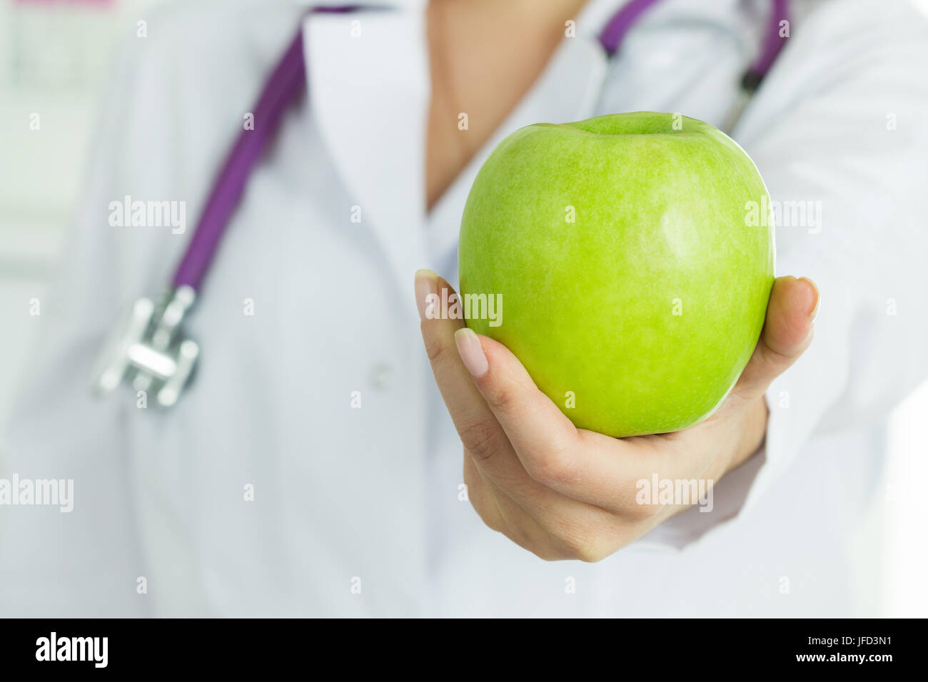 Female doctor's hand holding fresh green apple. Healthcare and medical ...
