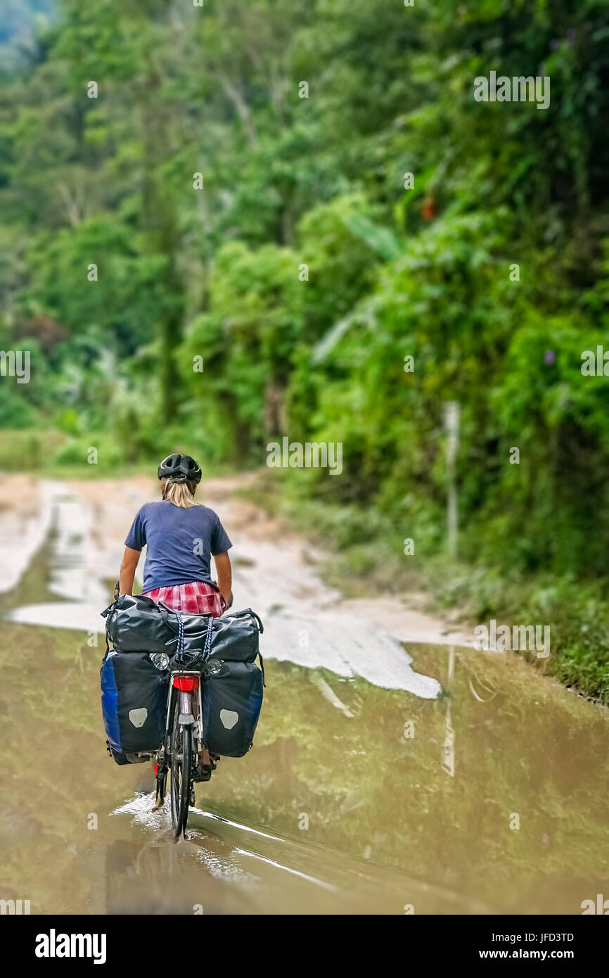Female cyclist cycling on Trans-sumatran Highway in Sumatra, Indonesia ...