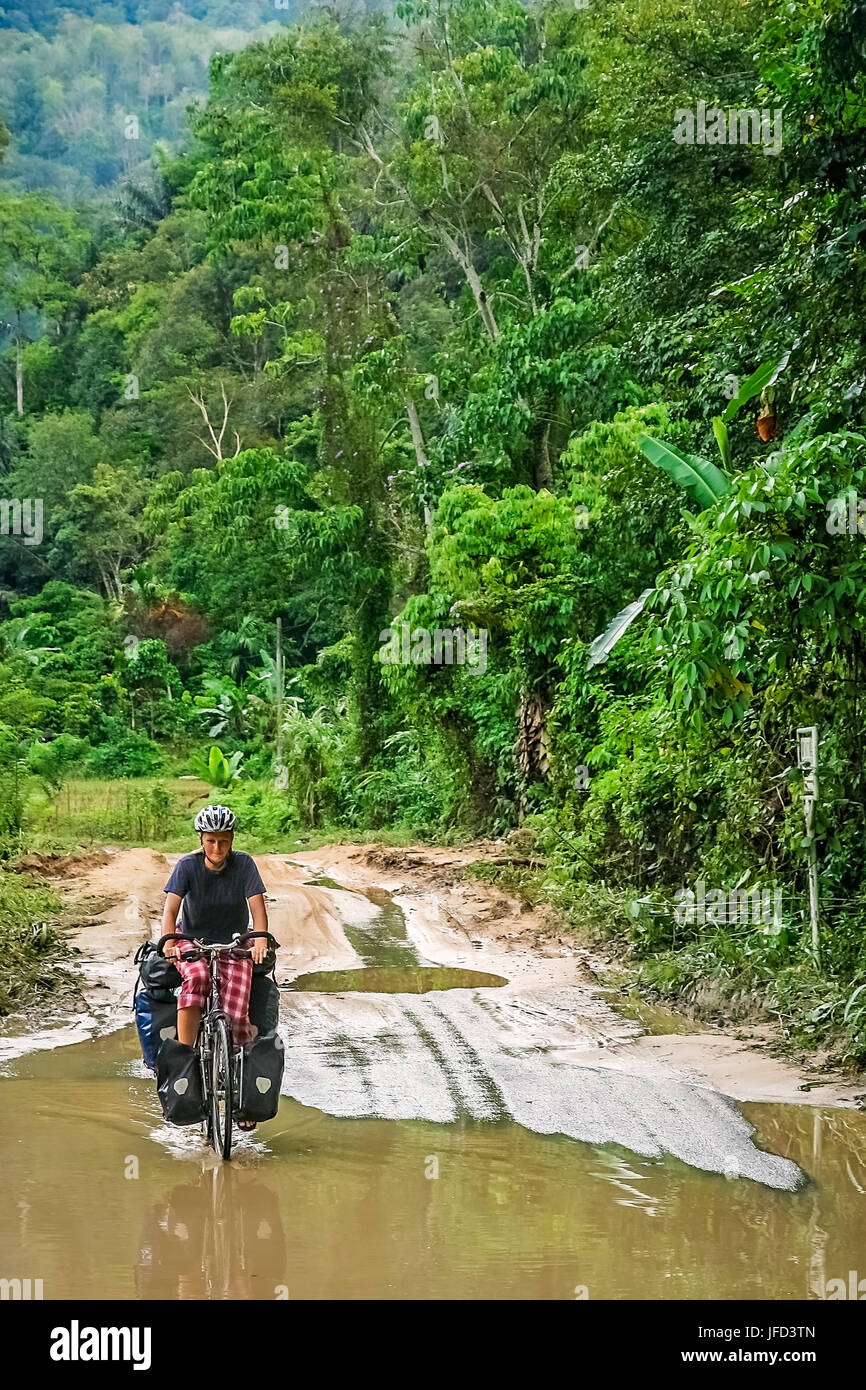 Female cyclist cycling on Trans-sumatran Highway in Sumatra, Indonesia ...