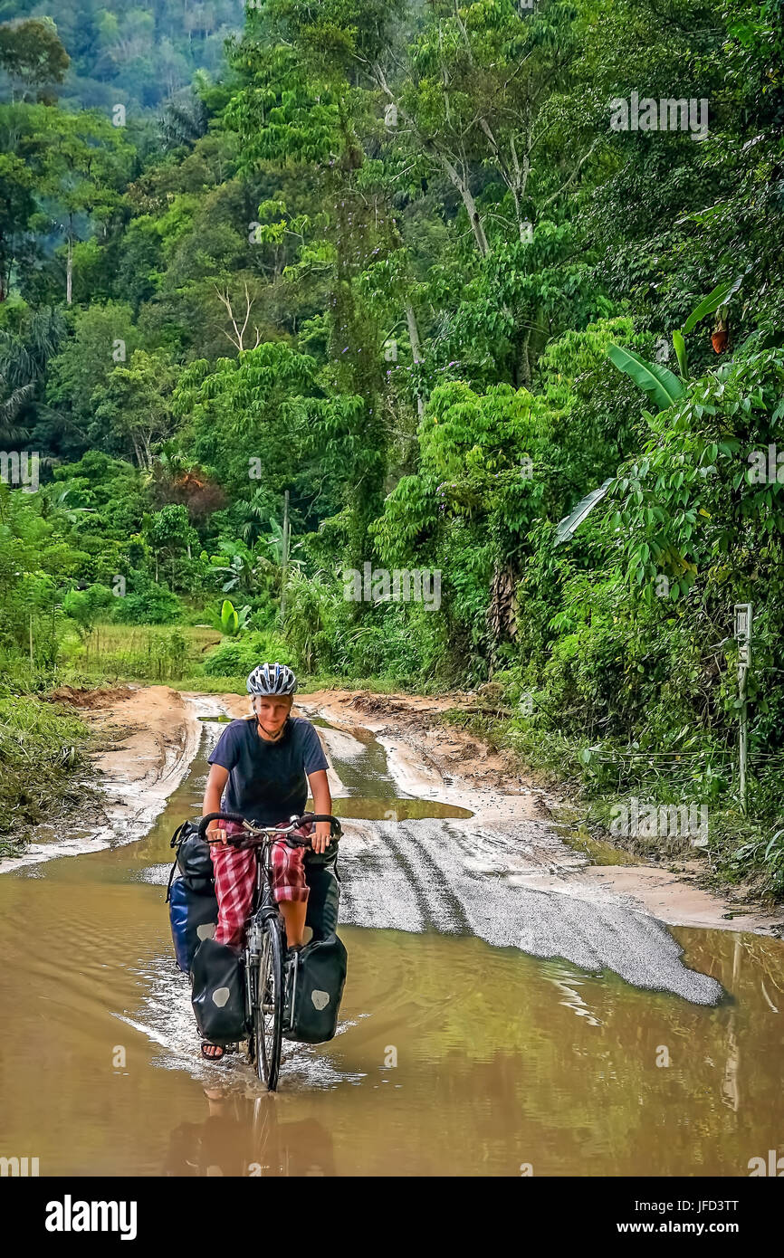 Female cyclist cycling on Trans-sumatran Highway in Sumatra, Indonesia ...