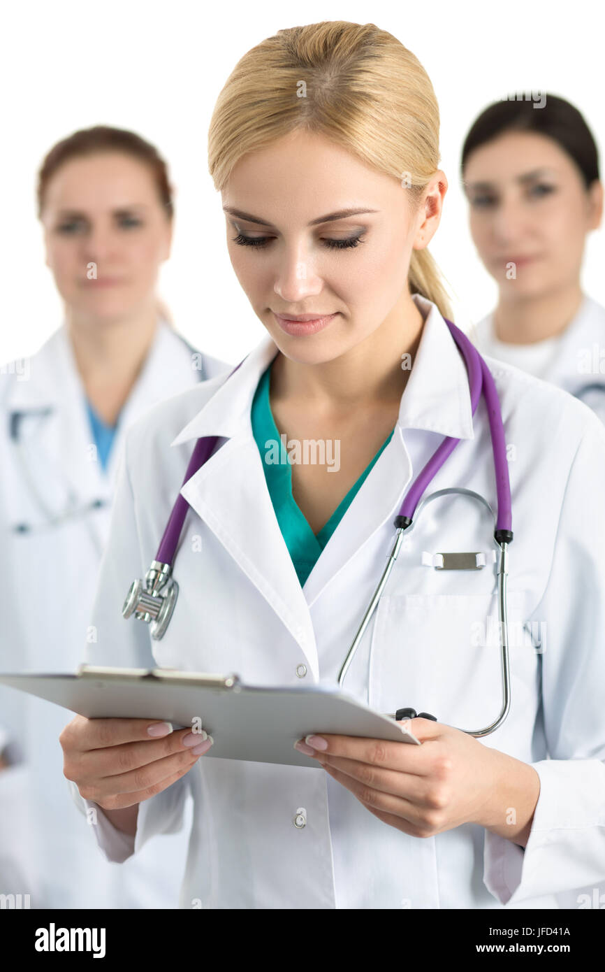 Portrait of young blonde female doctor surrounded by medical team ...