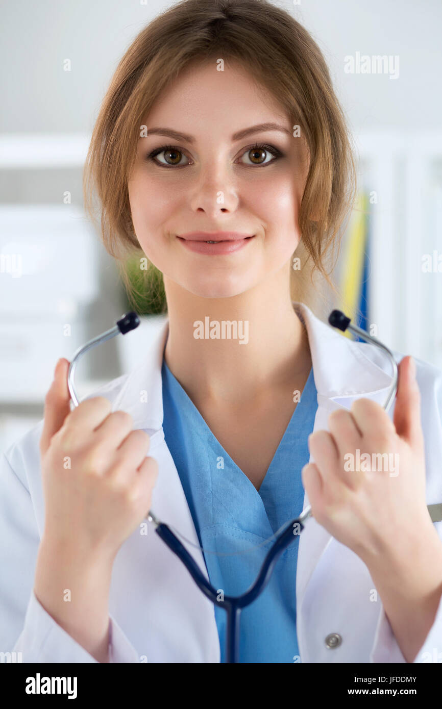 Beautiful smiling female medicine doctor holds and puts on stethoscope ...