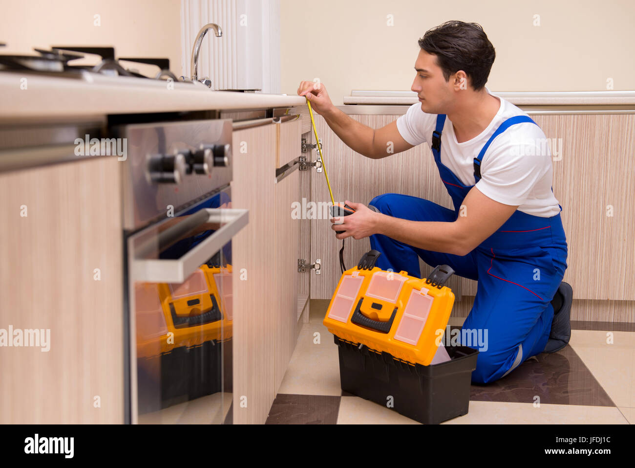 Young repairman working at the kitchen Stock Photo - Alamy