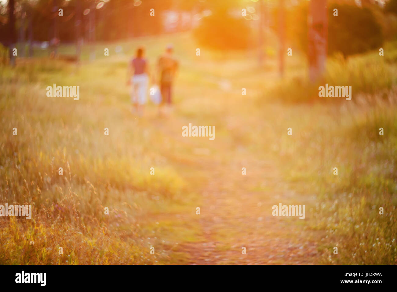 Couple walking on defocused path, sunset time Stock Photo - Alamy