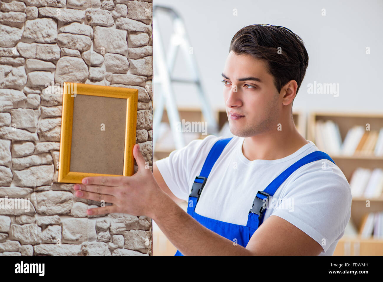 Repairman putting picture frame onto wall Stock Photo - Alamy