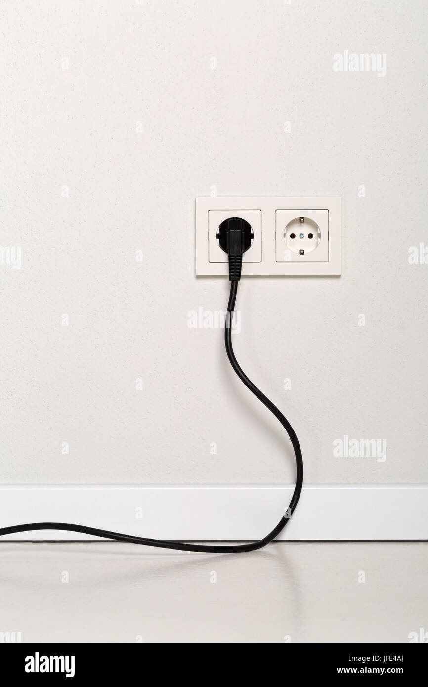 Black power cord cable plugged into european wall outlet on white ...