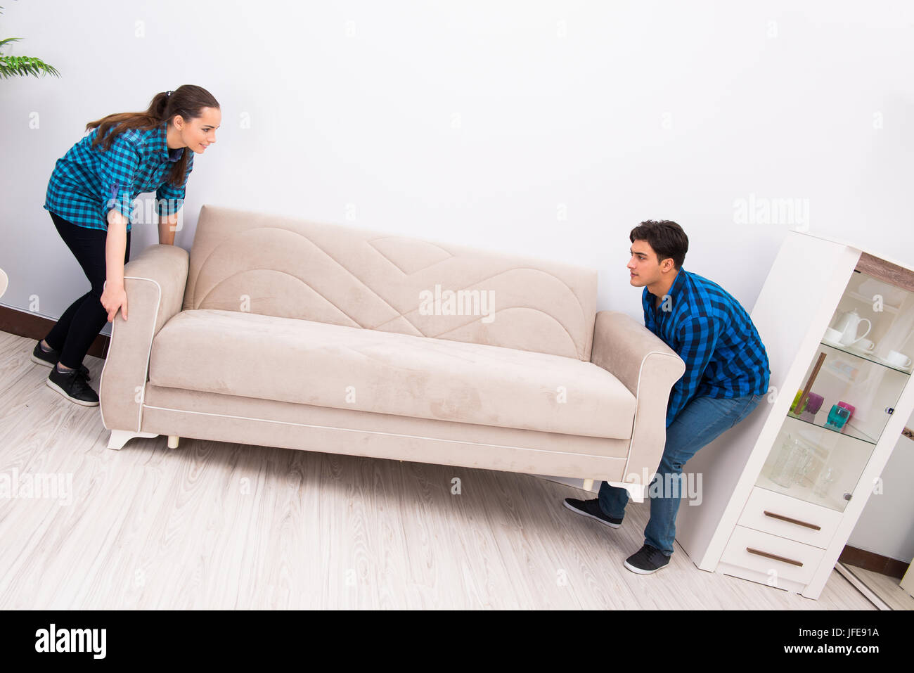 Wife and husband moving sofa couch Stock Photo - Alamy