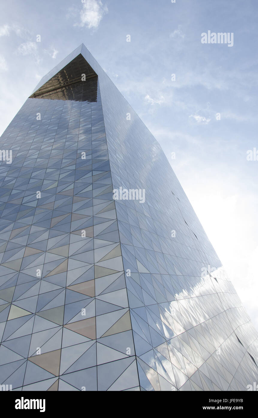 Skyscraper rising towards the cloudy sky reflecting the sky on its ...