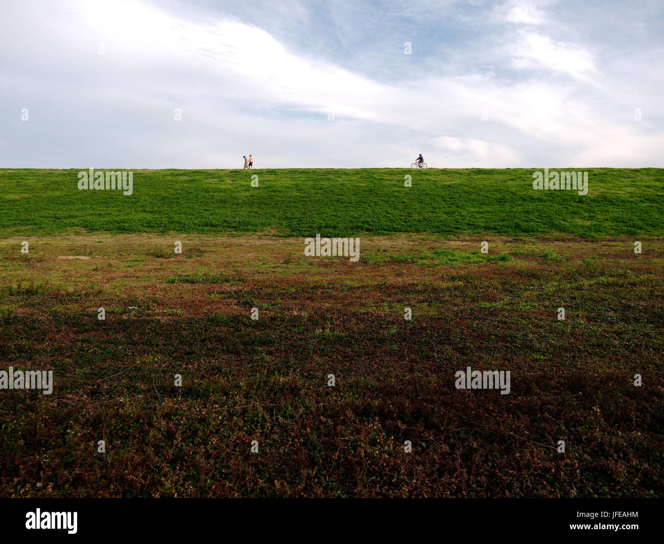 Empty field and sky with people far away on the horizon Stock Photo - Alamy