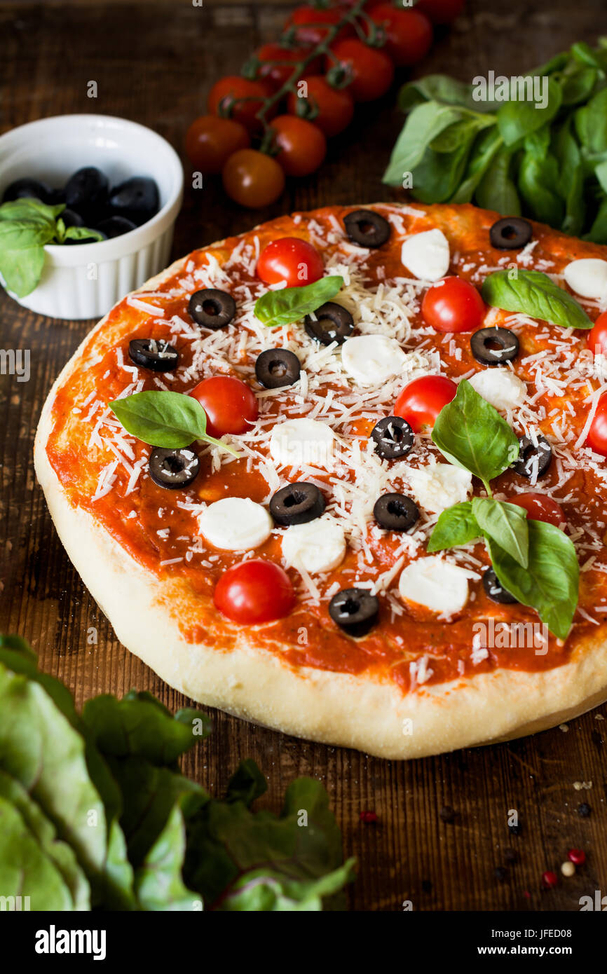 Pizza with tomatoes, mozzarella cheese, black olives and basil ...