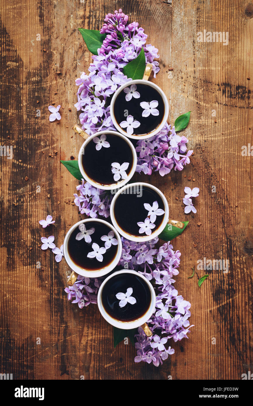 Still life composition with lilac flowers and cups of black coffee on ...