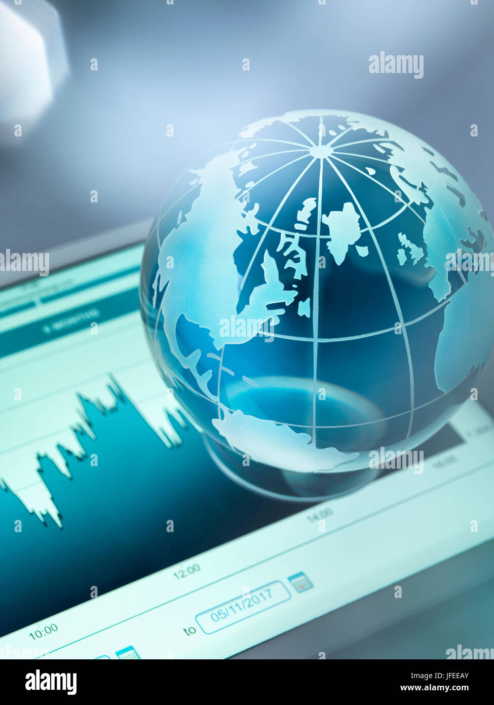 A glass globe illustrating the world sitting on a digital table showing ...