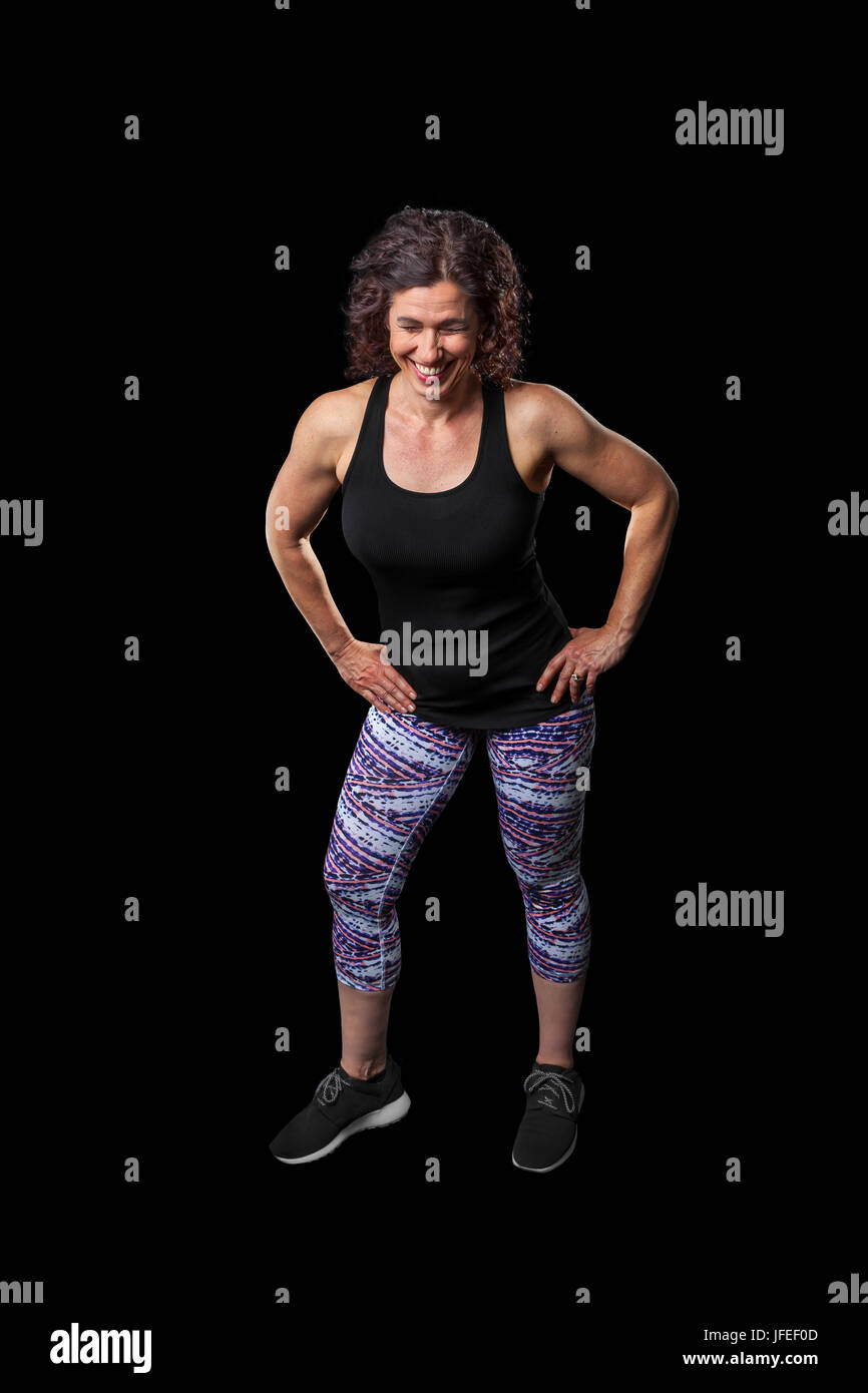 Full length portrait of muscular female laughing on black background ...
