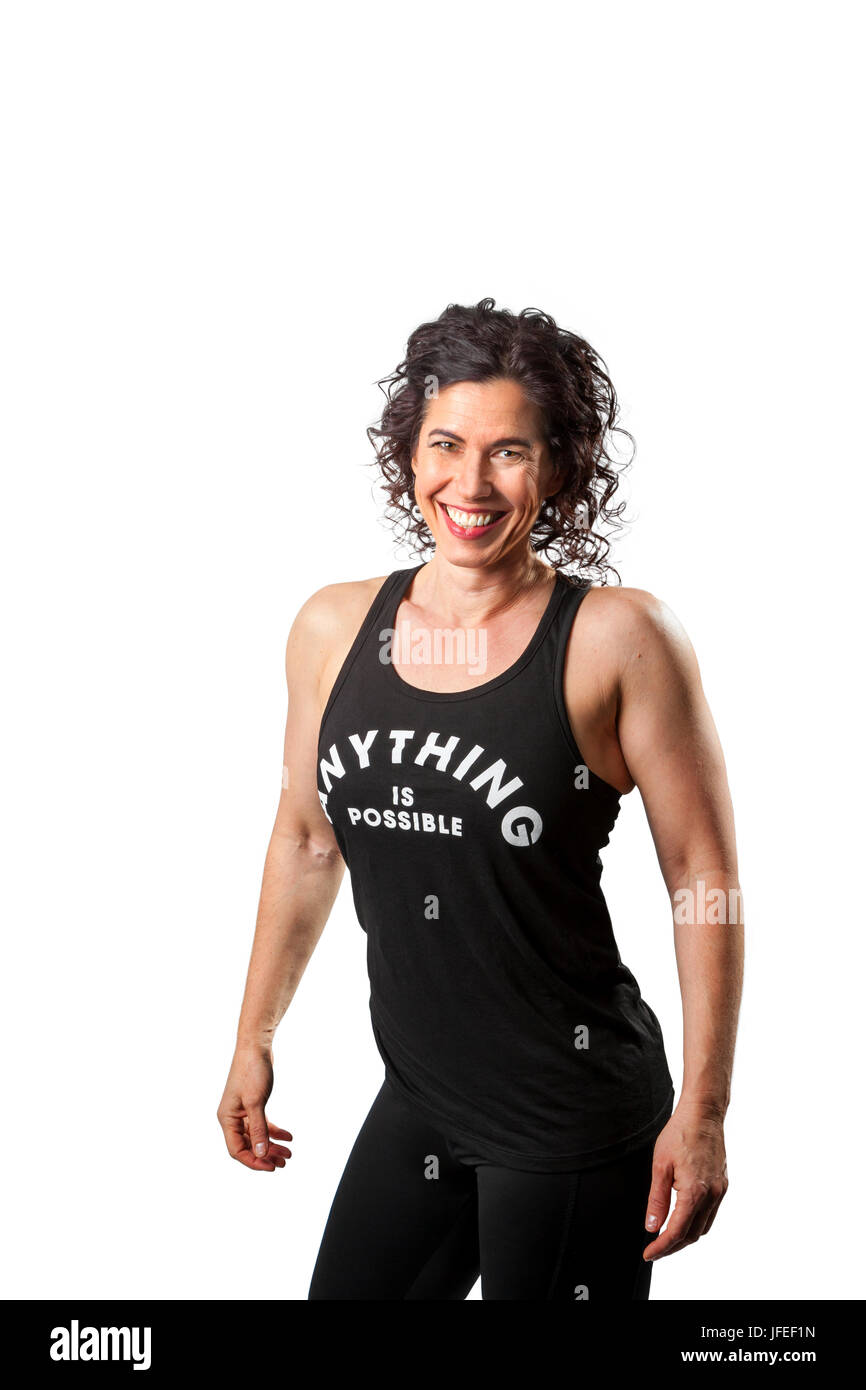 A beautiful, muscular, female trainer with dark, curly hair poses for a ...