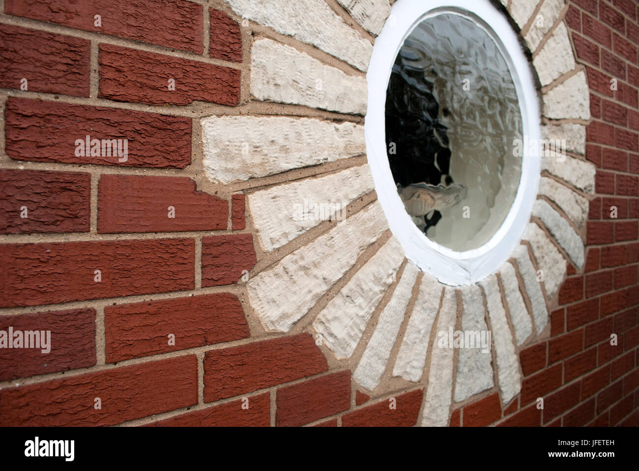 Round window surrounded by stone in red brick wall Stock Photo - Alamy