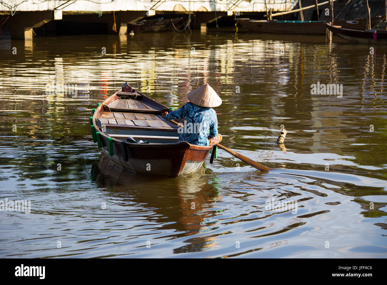 Woman in a rowboat lookoing for tourist customers on the Thu Bon River ...