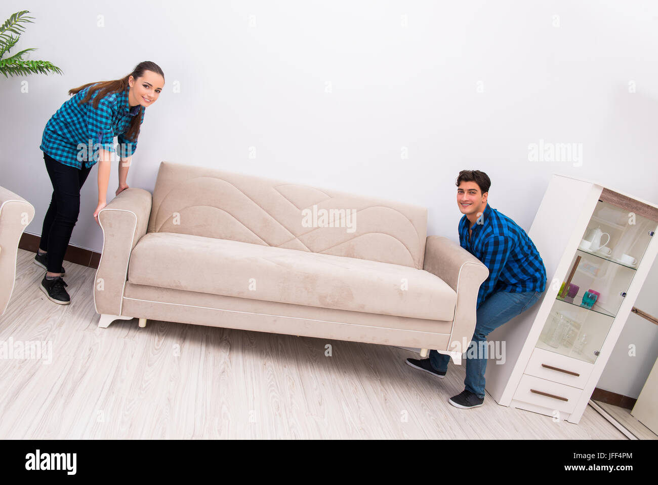 Wife and husband moving sofa couch Stock Photo - Alamy