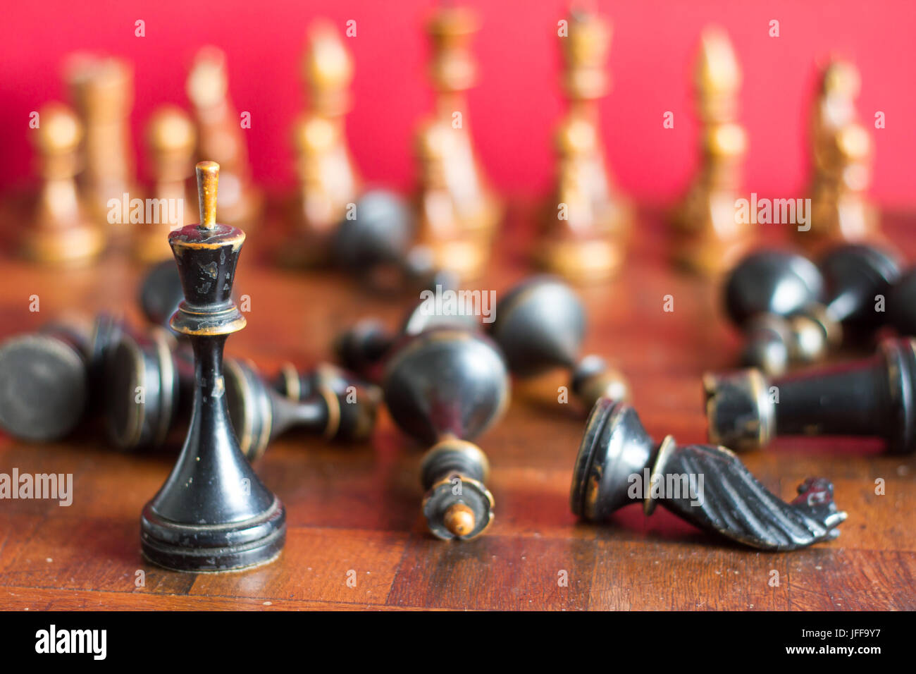 Ancient wooden chess pieces on an old chessboard. On a red background ...