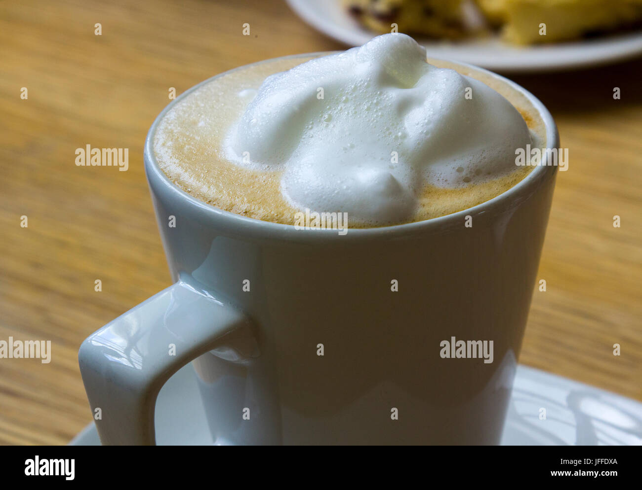 A large frothy topped hot cappuccino coffee in a plain porcelain cup ...