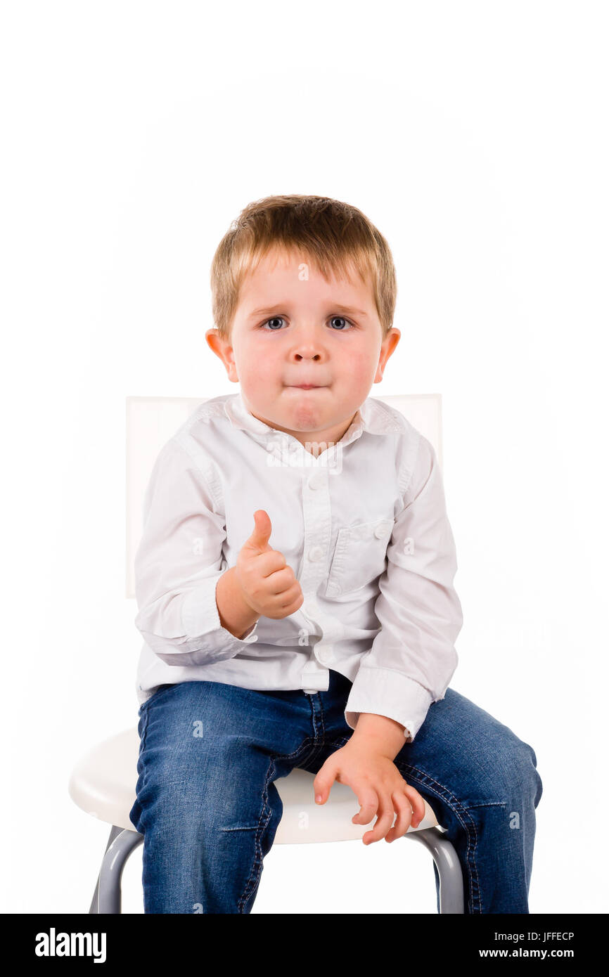 Cute little boy sitting on a stool giving a thumbs up. Isolated on ...
