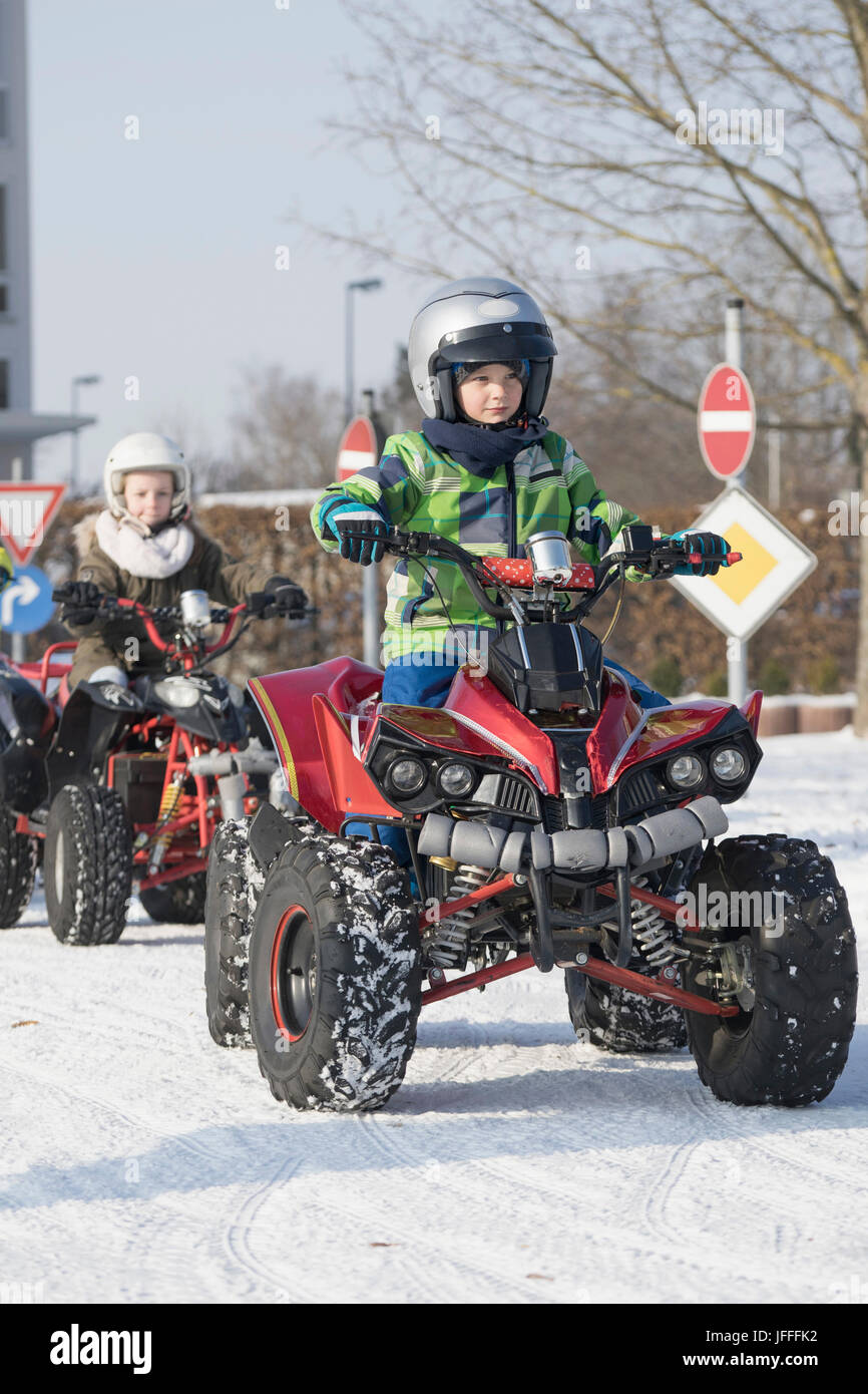 Children riding quad bike on snow Stock Photo - Alamy