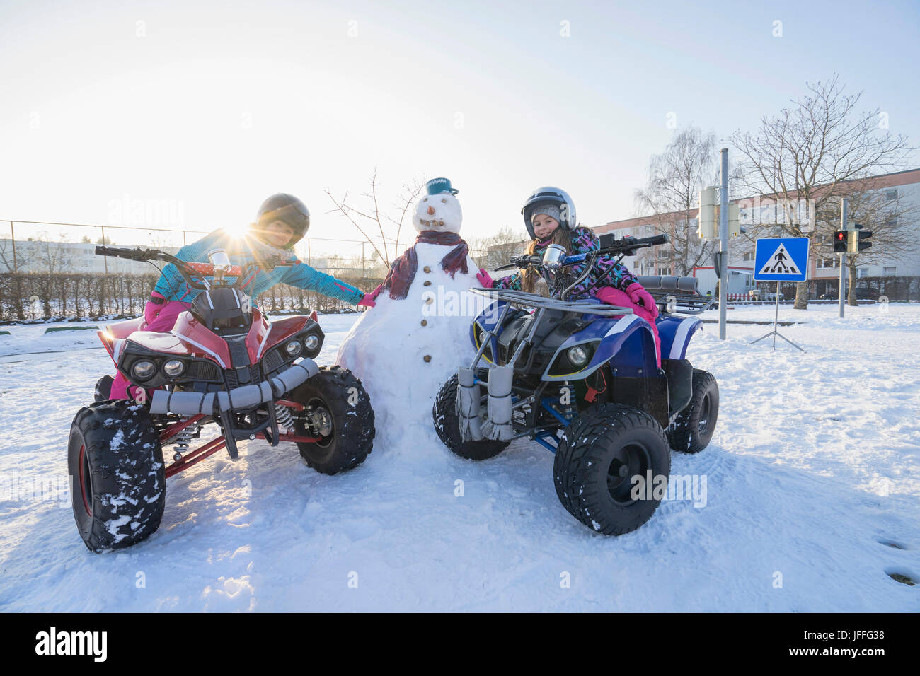 Girl riding quad bike and leaning on snowman Stock Photo - Alamy