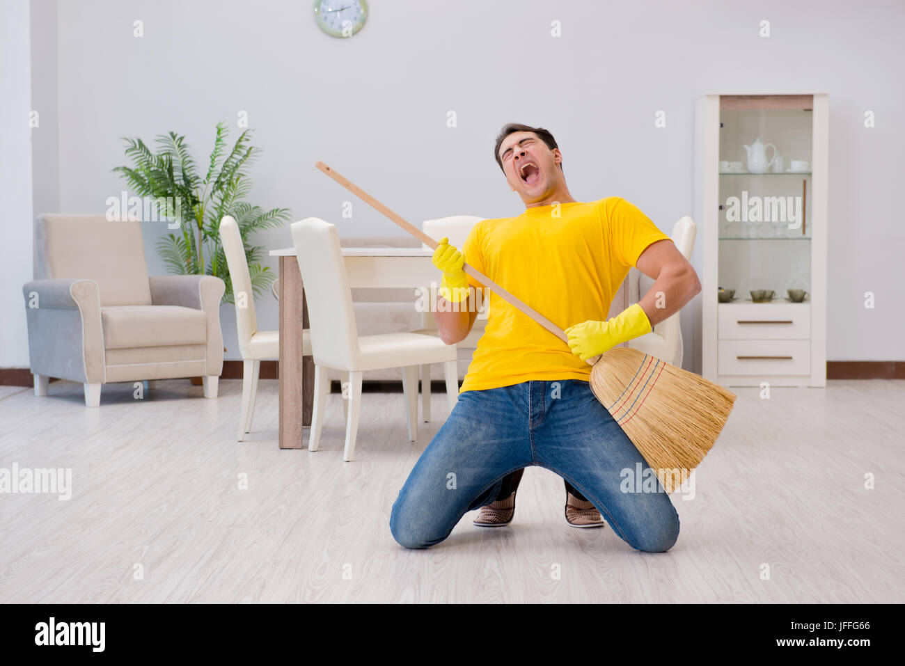 Funny man playing virtual guitar with broom Stock Photo - Alamy