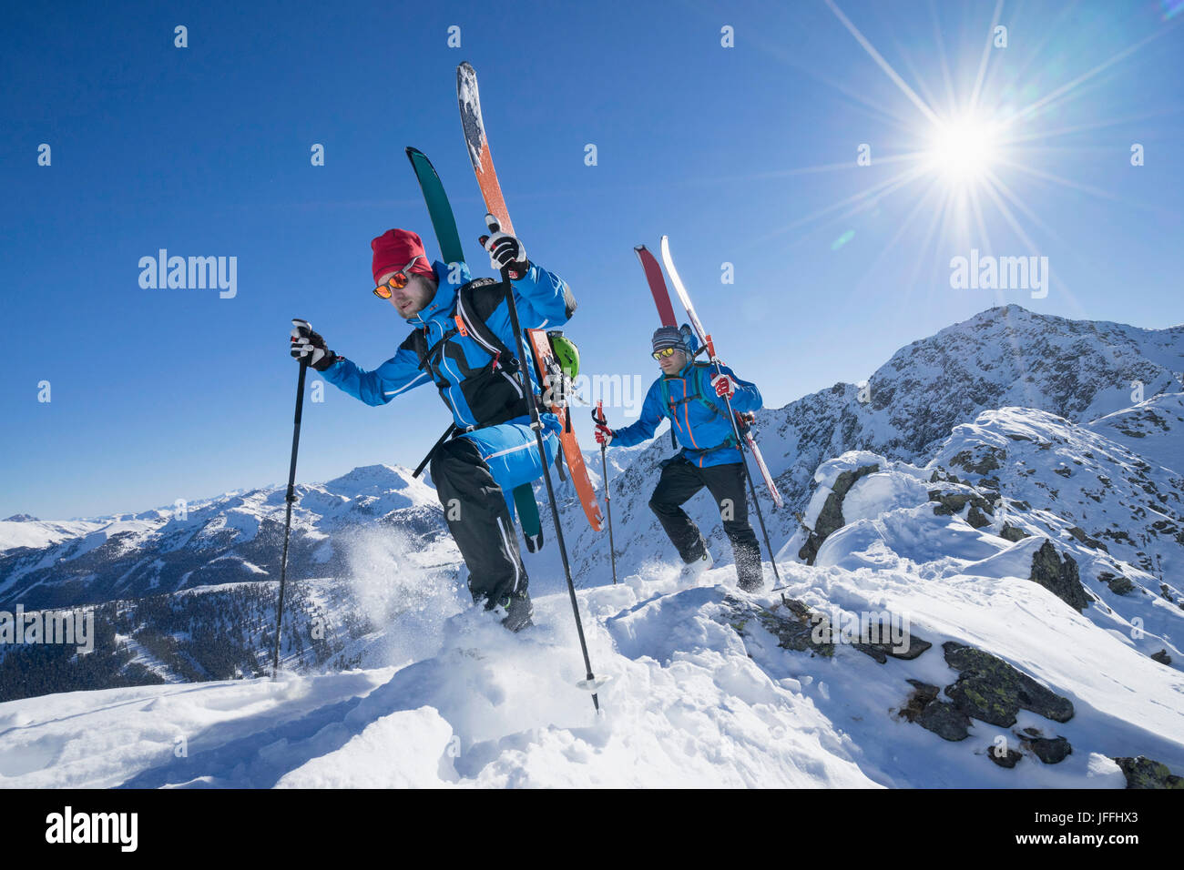 Skiers walking downwards on mountain slope Stock Photo - Alamy