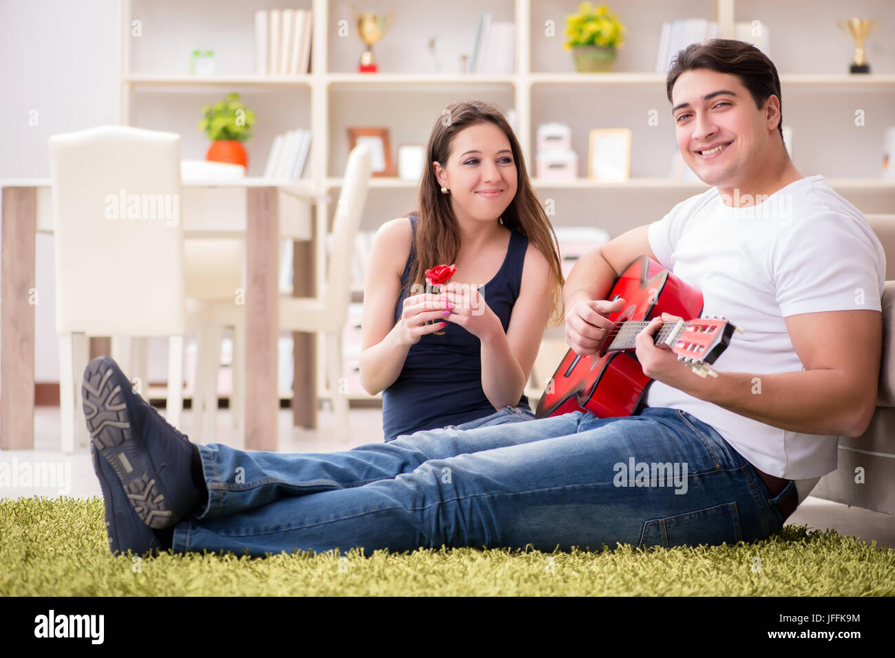 Romantic pair playing guitar on floor Stock Photo - Alamy