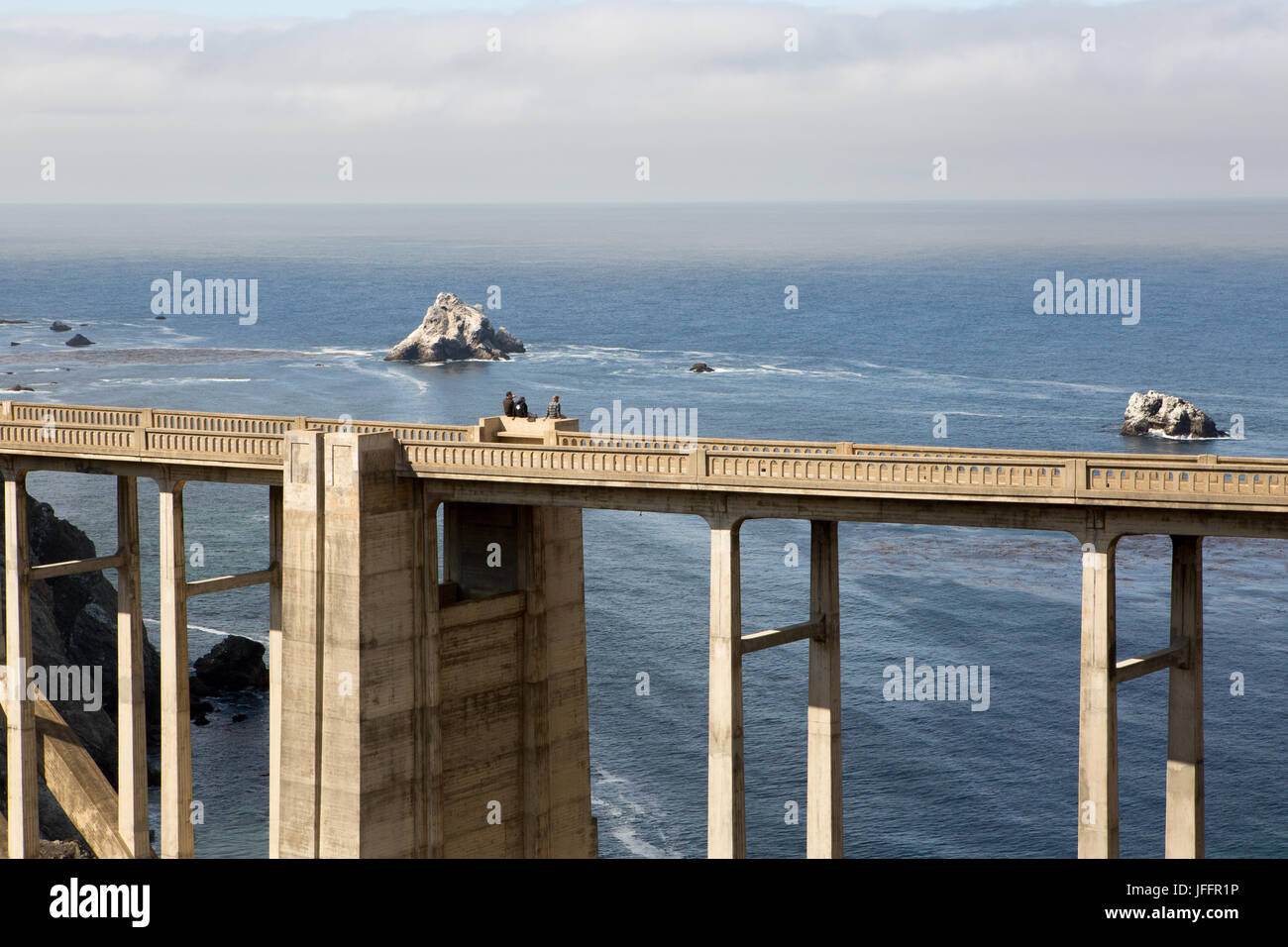 Several people sitting and sightseeing atop the Bixby Creek Bridge, a ...