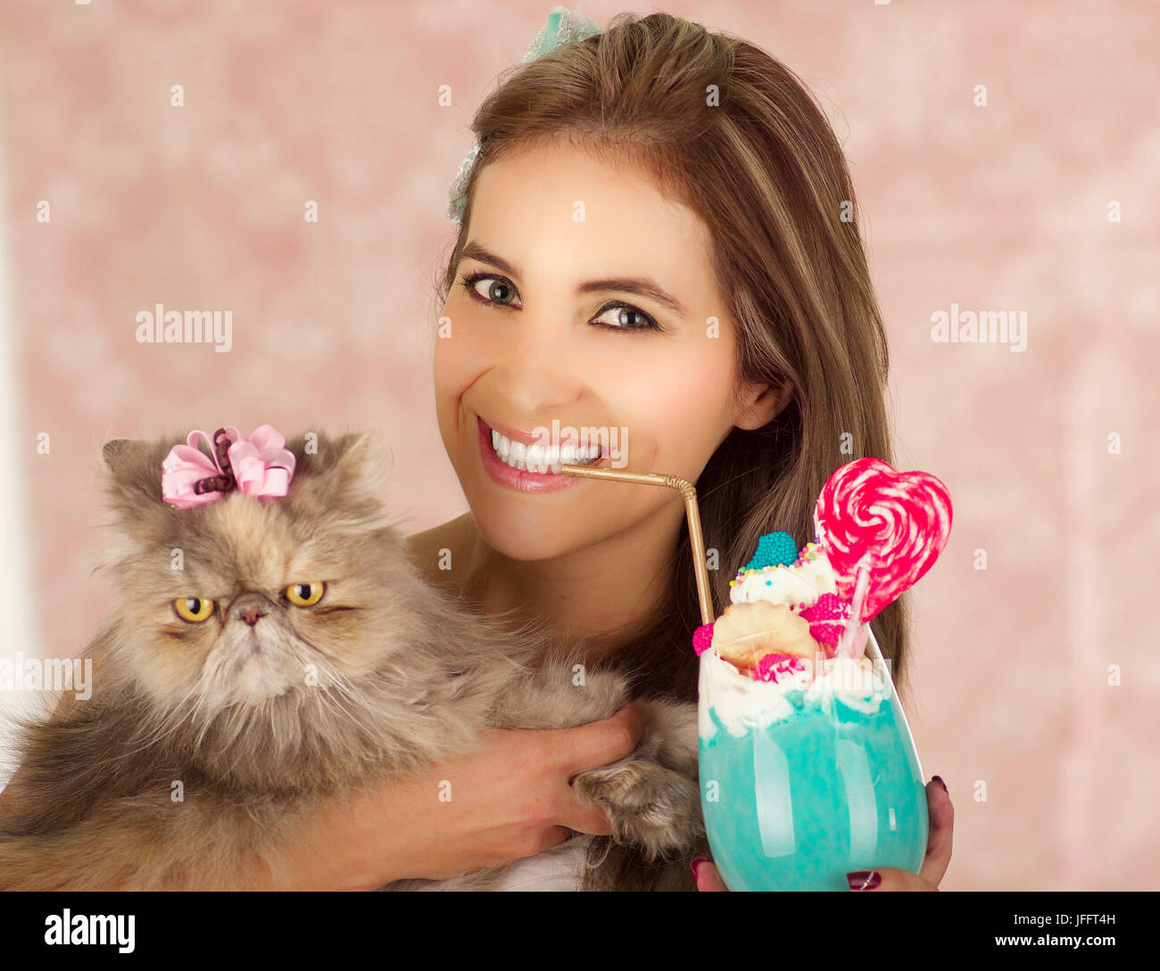 Smiling young beautiful woman with a tasty blue milk shake in studio ...