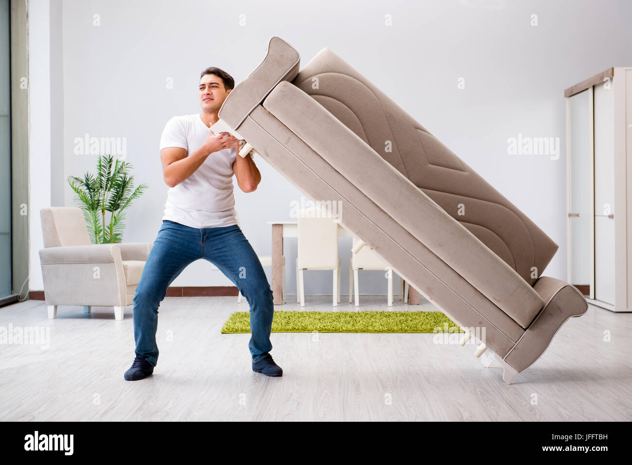 Young man moving furniture at home Stock Photo - Alamy
