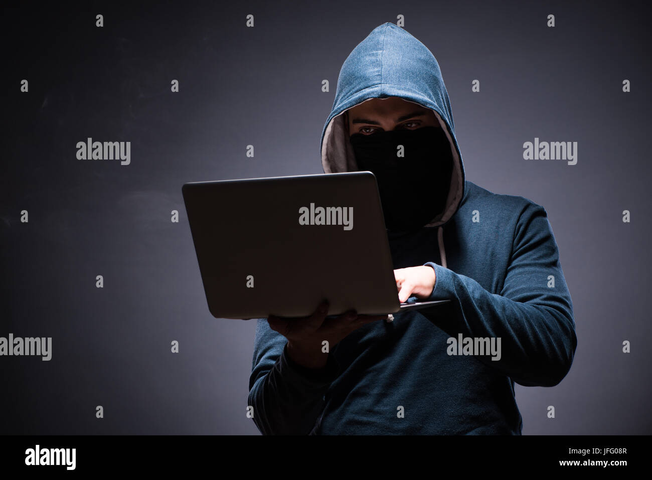 Hacker wearing hood in dark room Stock Photo - Alamy