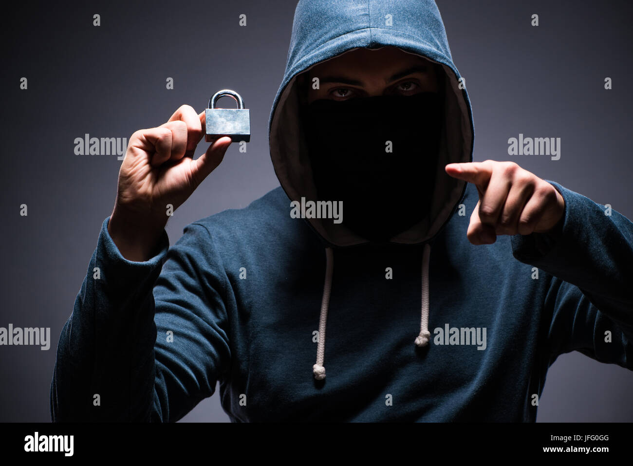 Hacker wearing hood in dark room Stock Photo - Alamy