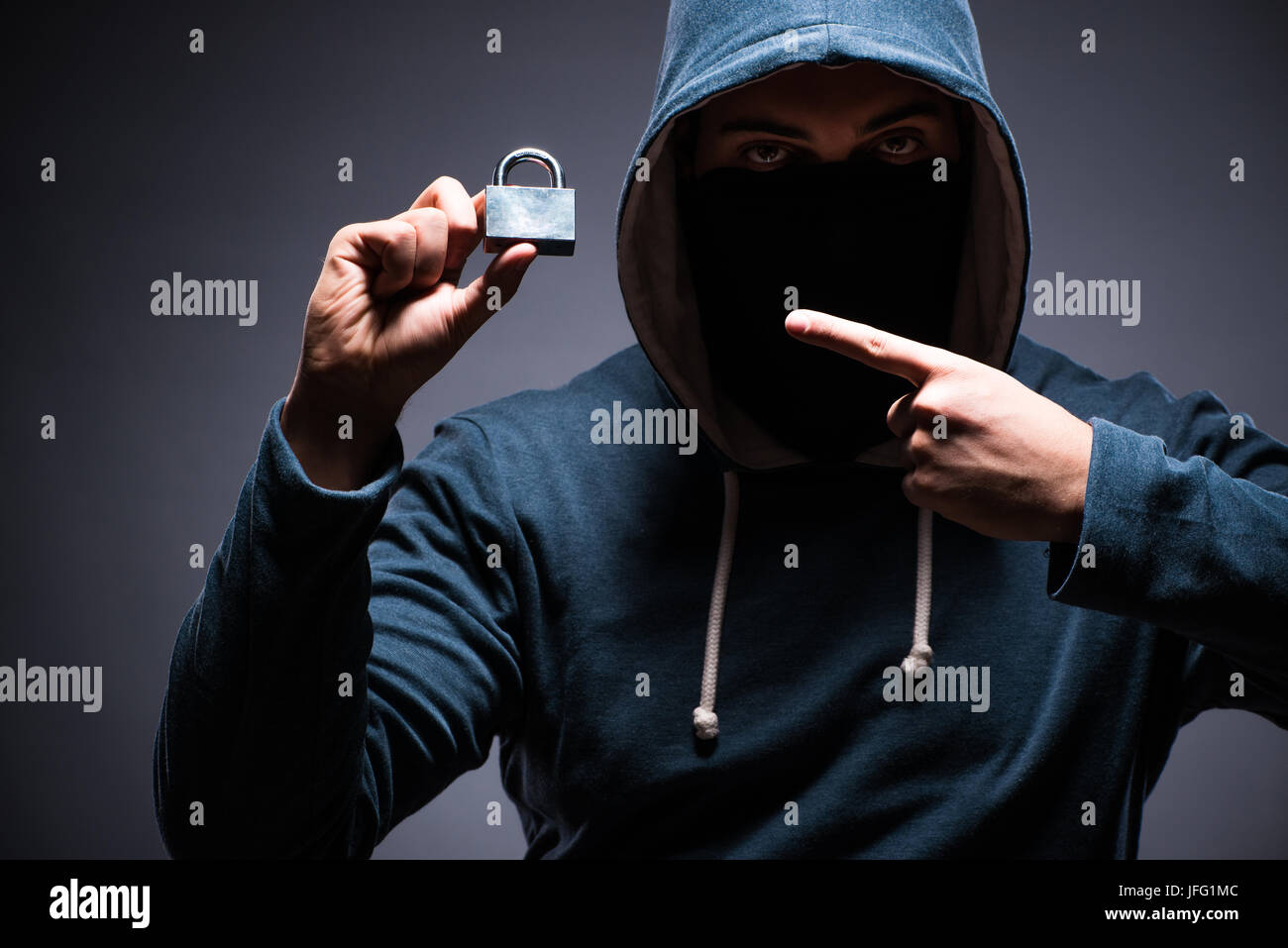 Hacker wearing hood in dark room Stock Photo - Alamy